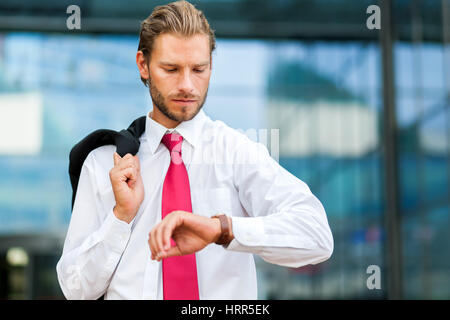 portrait of a handsome worried businessman checking the time on his ...