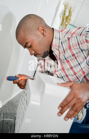 African american man holding screwdriver wearing ear protection at home ...