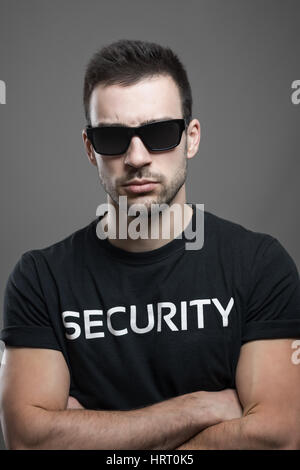 Tough serious bouncer or bodyguard with crossed arms staring at camera ...