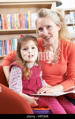 happy child reading book on bean bag chair isolated on pink Stock Photo ...