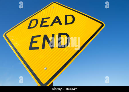 yellow and black dead end road sign in the desert with bullet holes ...