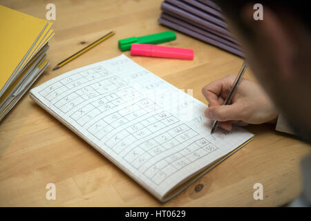 Primary school teacher marking pupils homework study books at home in ...