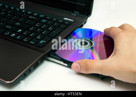Man insert compact disc from laptop Stock Photo - Alamy