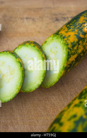 slices unusual green-orange zucchini and red chilly on an old wooden ...