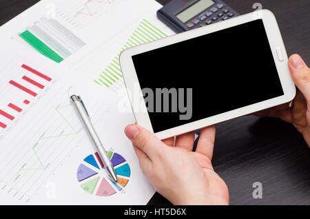 Modern tablet computer with business charts on screen against grey ...