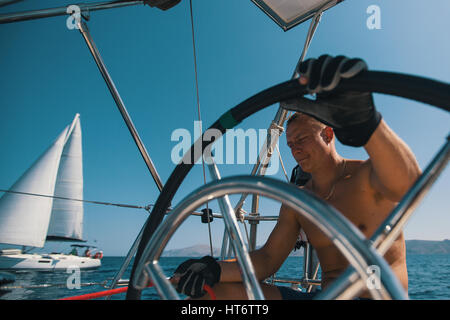 Man skipper at the helm controls of a sailing yacht during sea boats ...