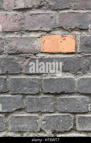 A red brick wall with many of the bricks having black spots on them ...