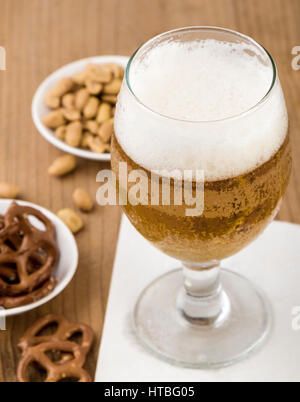 Glass mug with fresh cold beer on wooden bench in winter outdoor cafe ...