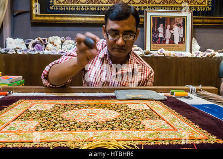 A man creating an embroidered Zardozi wall hanging viewed from above ...