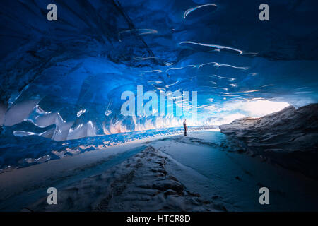 Man stands inside an ice tunnel under the Black Rapids Glacier, Alaska ...