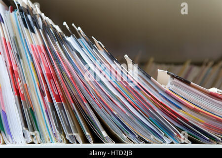A stack of patient medical records in folders with color-coded and ...