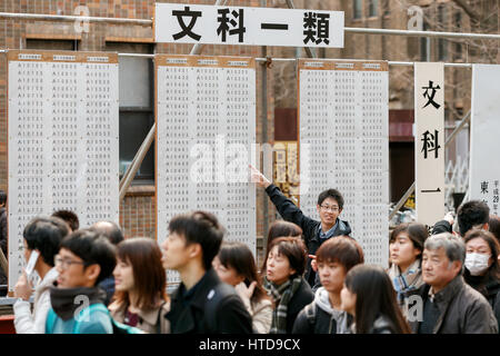 A Japanese student points his exam number on the list at the University ...