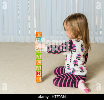 Little Caucasian girl knocking at the wooden doors of a green house ...