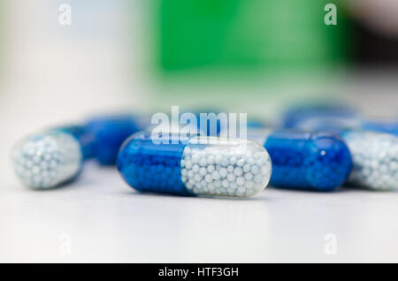 Blue Capsule with white drug balls inside isolated on blue. 3D ...