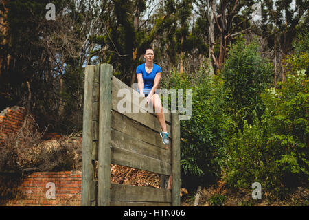 Woman climbing over over wall Stock Photo - Alamy