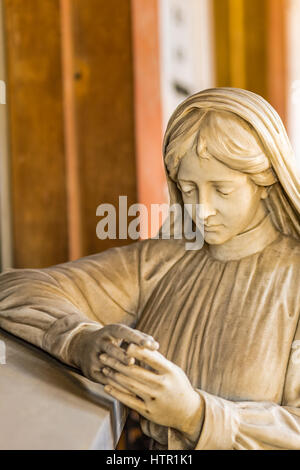 statue of sad woman looking down with reclined head and hands together ...