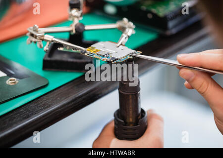 A man is repairing a mobile phone. In the frame, his hands and details ...