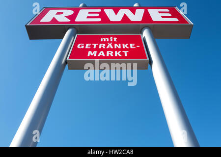 REWE sign (with beverage store) against blue sky. REWE operates ...