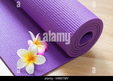a roll of yoga mat on the wooden floor, doing exercise in the gym ...