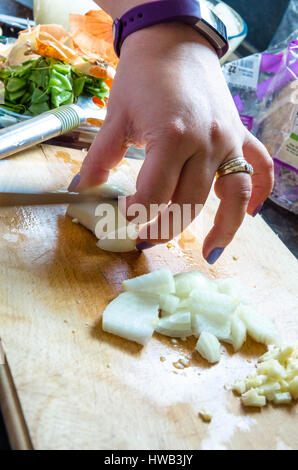 A wooden cutting board holds a knife, a piece of sliced salami, and a ...