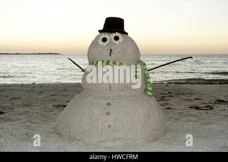 sandy Snowman in the sand on the beach with surfboard on the background ...