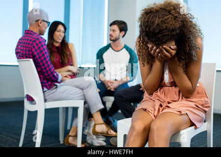 Woman crying while creative business team in background at office Stock ...
