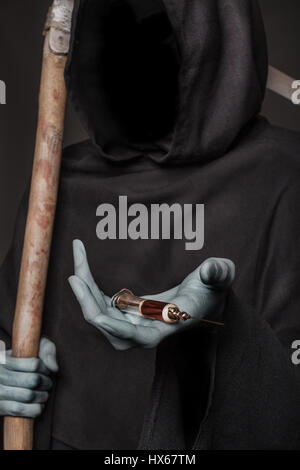 The concept: drugs kill. Grim reaper holding syringe with drugs. Studio ...