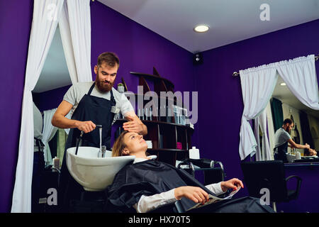 Master washes the head of the client in the Barber shop, hairdresser ...