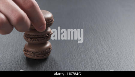 man hand stacking chocolate macarons on slate board, 4k photo Stock ...