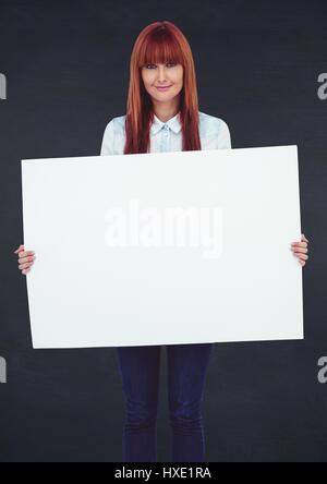 Doctor standing and smiling with chalkboard at hospital with copy space ...