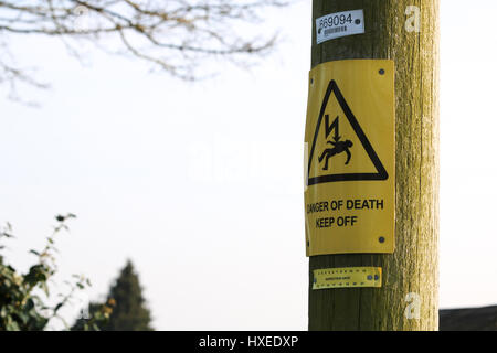 A yellow "Danger of Death" "Keep Off" warning sign typical in the UK ...