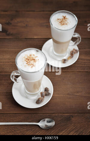 Delicious coffee with milk in glass cup and beans on wooden table ...