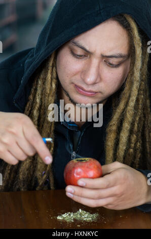 Man creating an apple bong using knife and a plastic tube, drug ...