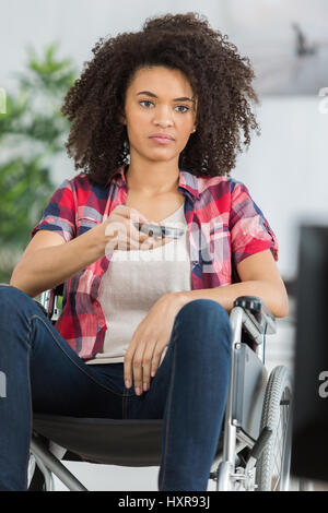 woman in wheelchair using remote control Stock Photo - Alamy