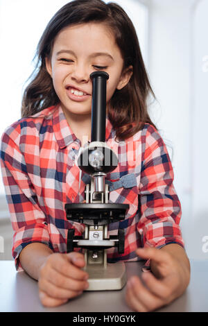 Pupil looking through microscope Stock Photo - Alamy