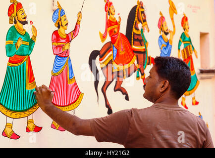 A man painting traditional Rajput designs onto a home to celebrate a ...