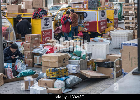 Chinese delivery men sort parcels by the road in Beijing, China. 01-Apr ...