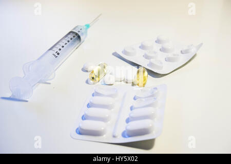 A variety of medication including a syringe with a green tip, blister ...