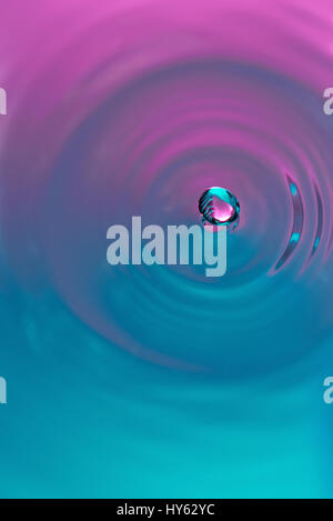 Closeup of a small water droplet splashing on a water surface with ...