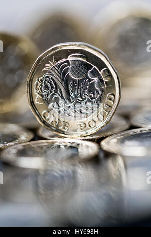 A stack of sterling £1 coins in front of different denomination ...