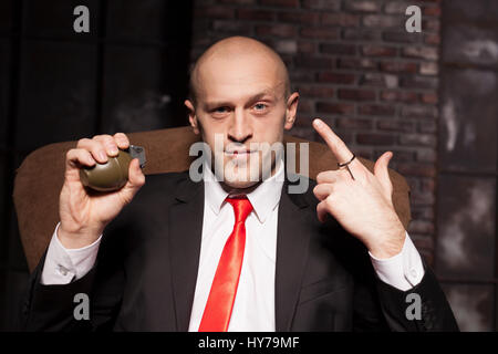 Bald special agent in suit and red tie pulls a grenade pin, dangerous ...