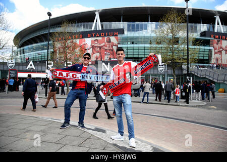 Arsenal fans pose for a picture holding scarves outside the ground ...