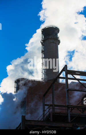 Factory smokestack releasing pollution smoke against a winter mountain ...