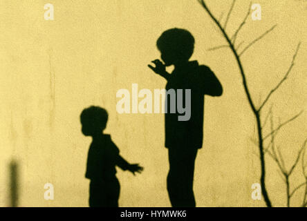 kid's shadows on wall. shadow of two children, boy and girl on striped ...