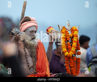 A bearded holy man poses in front of an intricately carved temple wall ...