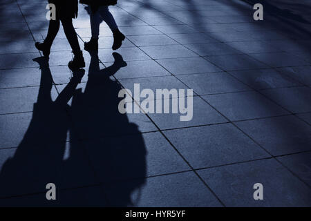 Two shadows walking in a dark empty tunnel towards bright light ...
