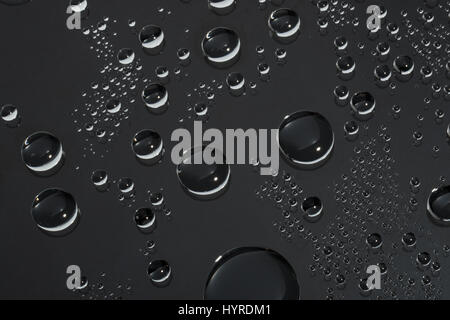 Round shaped water droplets on glass surface. Dark background behind ...