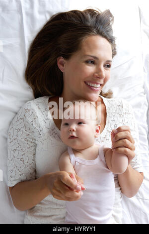 From above young mother holding on hands and breastfeeding newborn baby ...