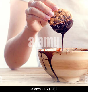 Woman's hand dipping a cookie in a bowl of milk isolated on a black ...