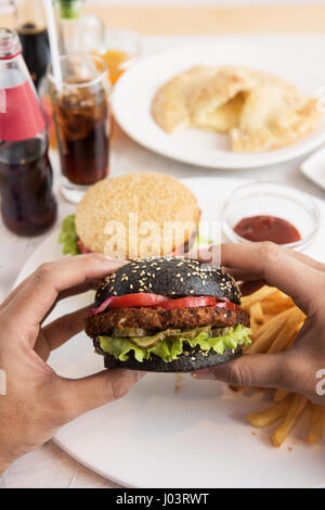 Man eating burgers at table, pov view Stock Photo - Alamy